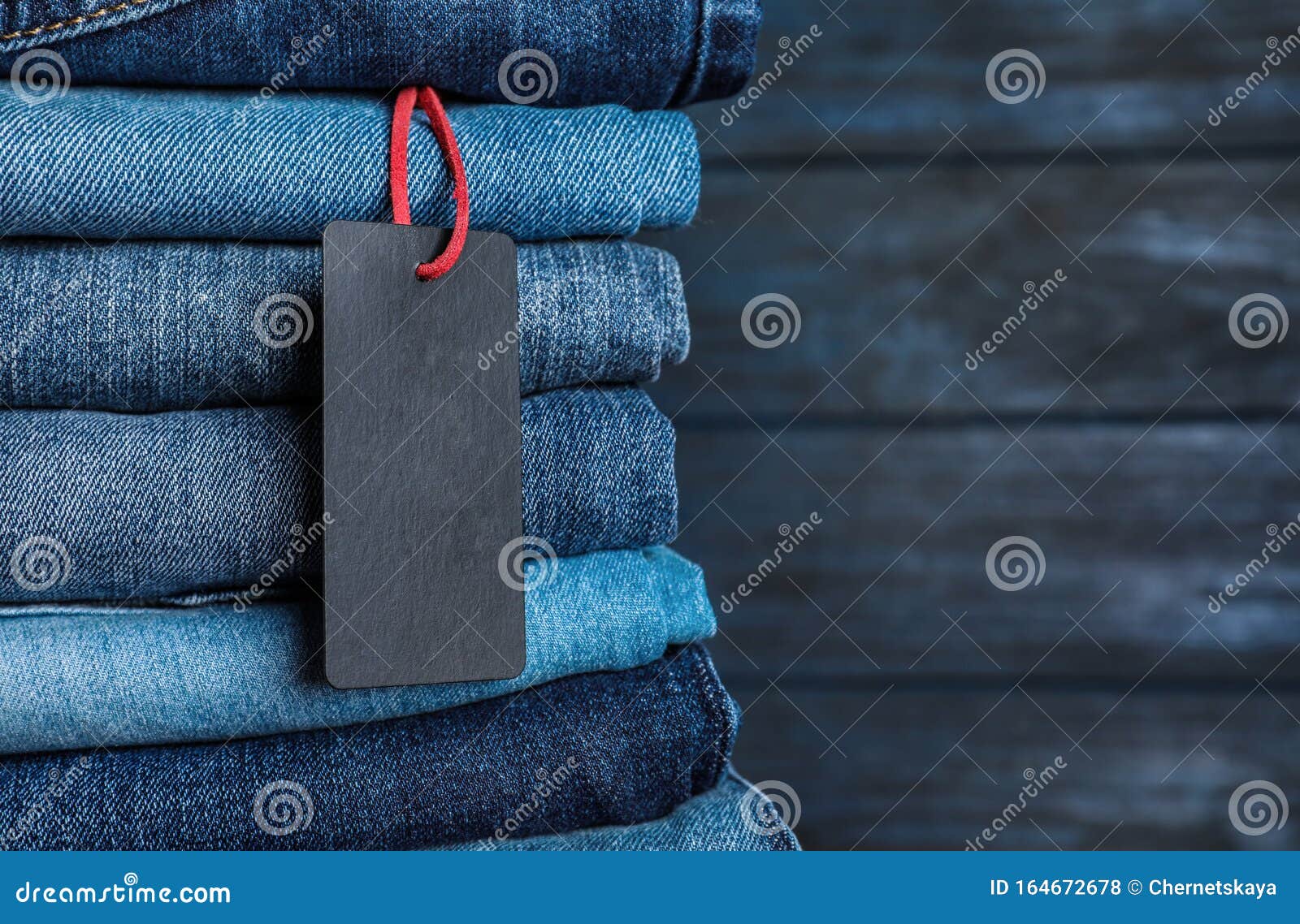 Stack of Different Jeans with Tag on Background, Closeup. Space for ...