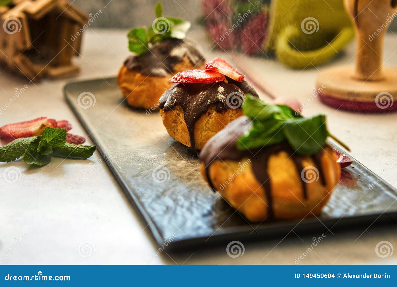 Stack Eclair of Profiteroles with Dark Melted Chocolate on a Black Dish ...