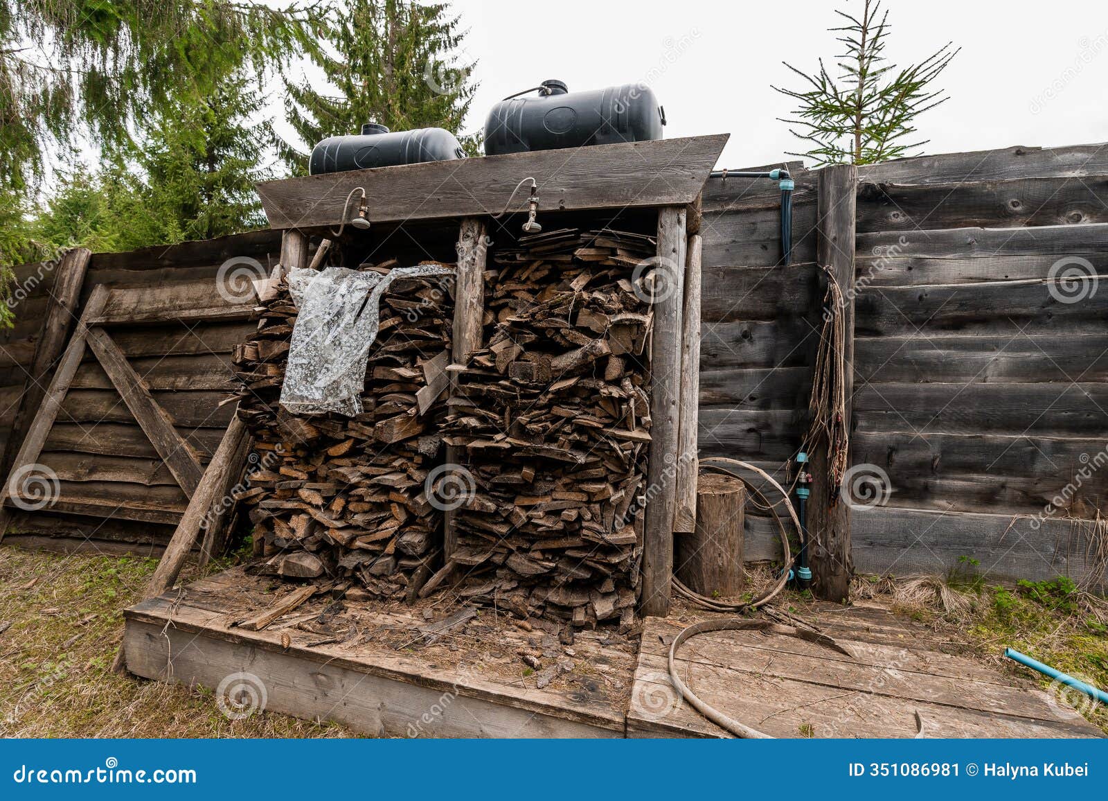 Stack of Firewood with Storage Tanks and Rustic Wooden Structure Stock ...