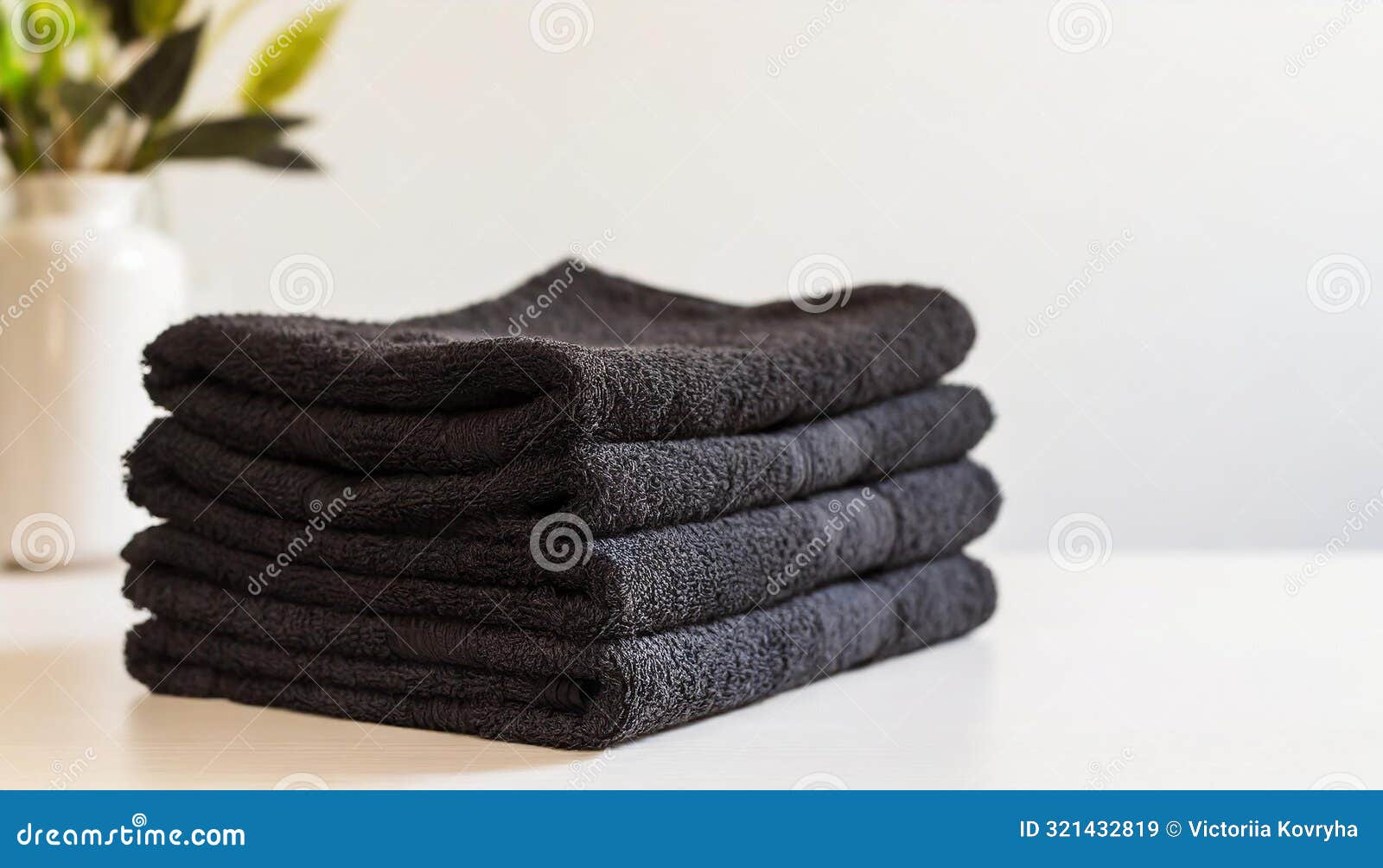 Stack of Folded Black Towels on Table, Light Wall on Background. Home ...