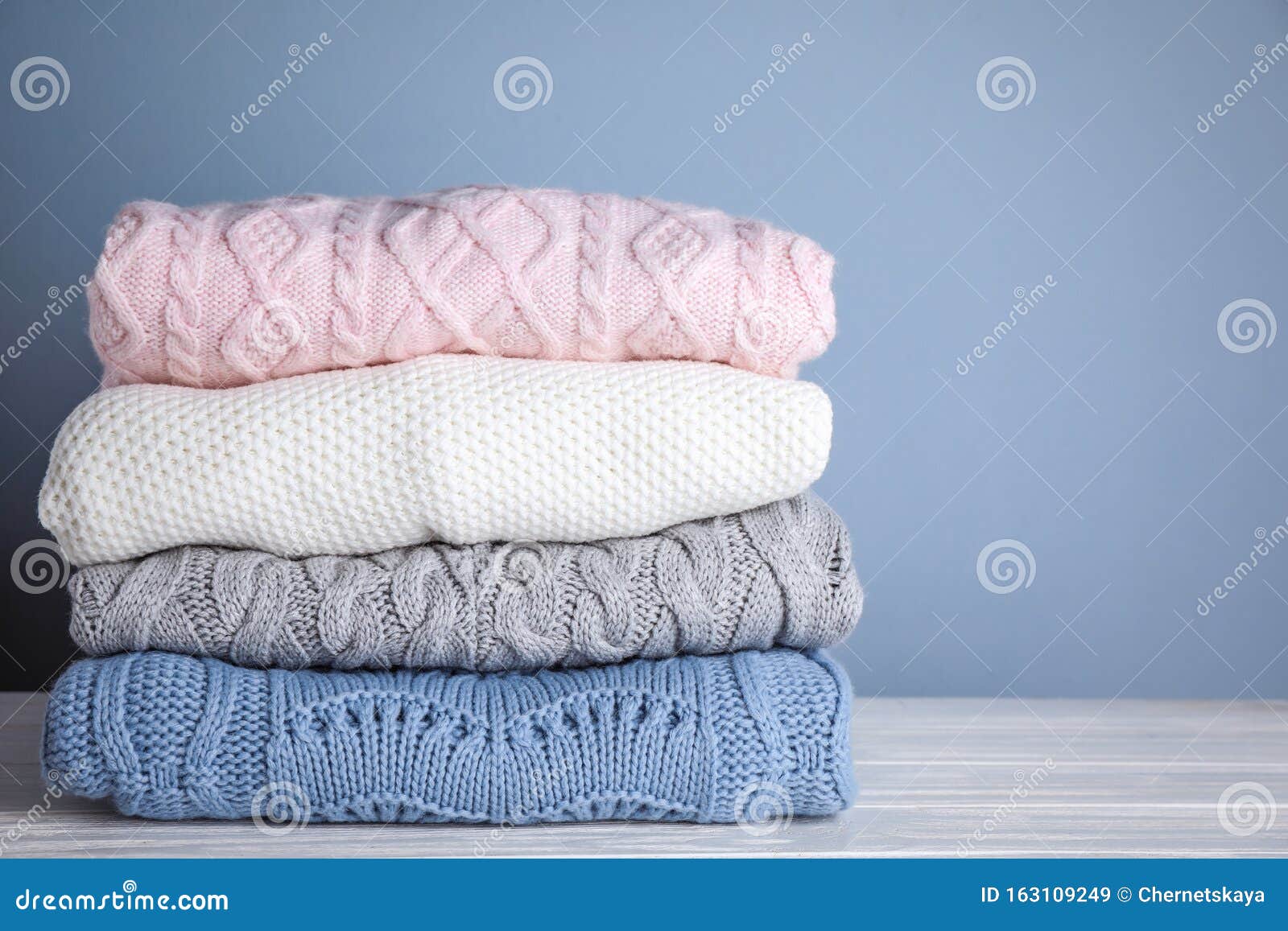 Stack of Folded Knitted Sweaters on White Wooden Against Grey ...