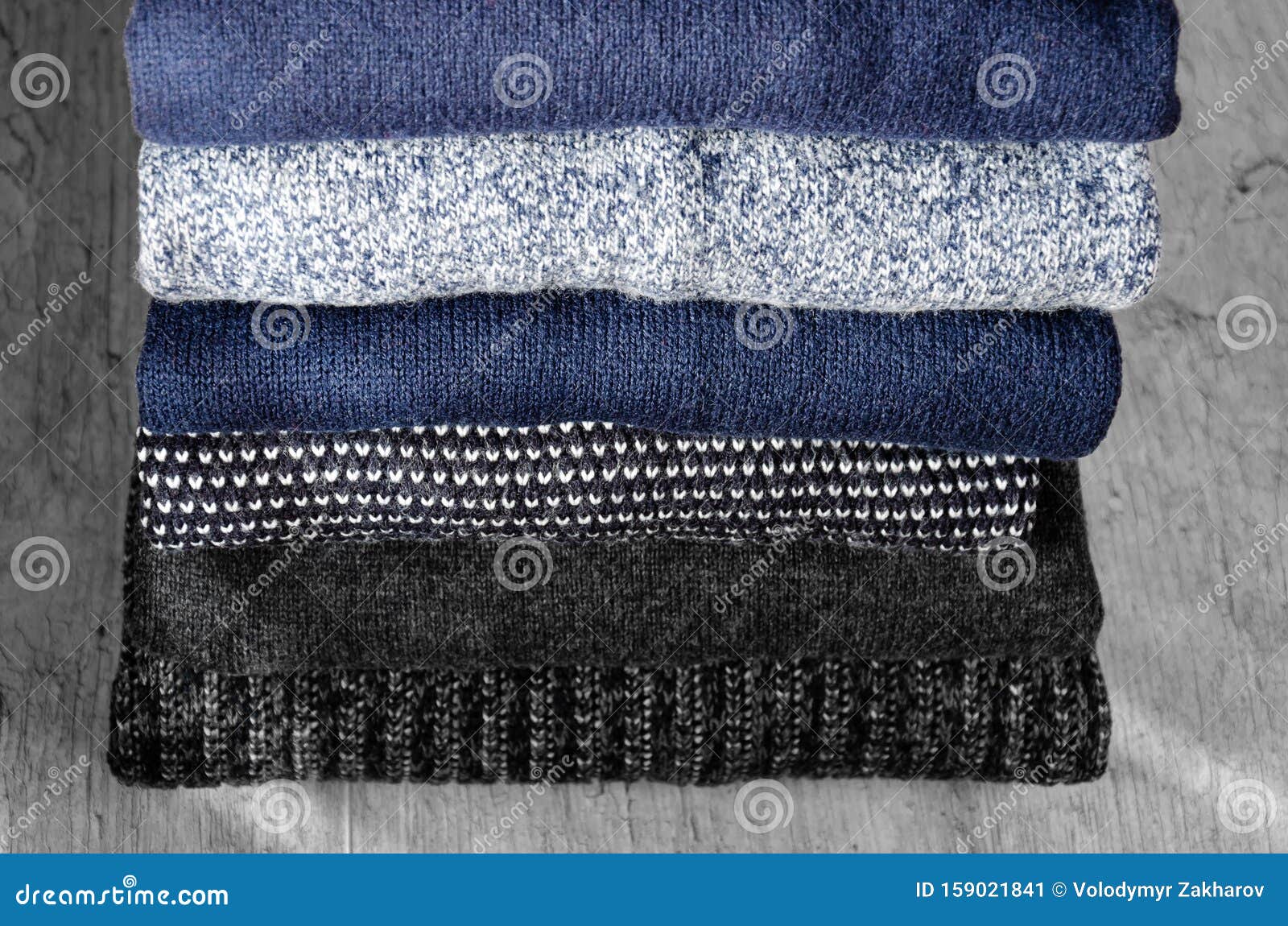 Stack of Folded Warm Knitted Men`s Sweaters on Gray Background. Closeup ...