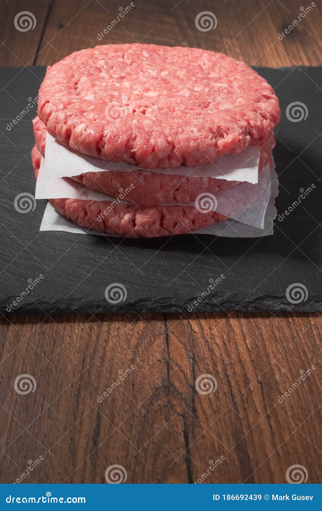 Stack of Fresh Uncooked Beef Burgers Separated by Cooking Paper on a ...