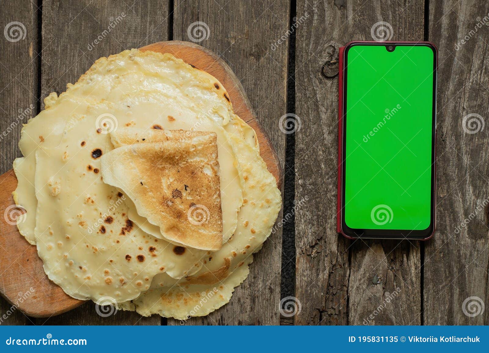 Stack of Fried Pancakes on a Wooden Table and a Phone with a Green ...