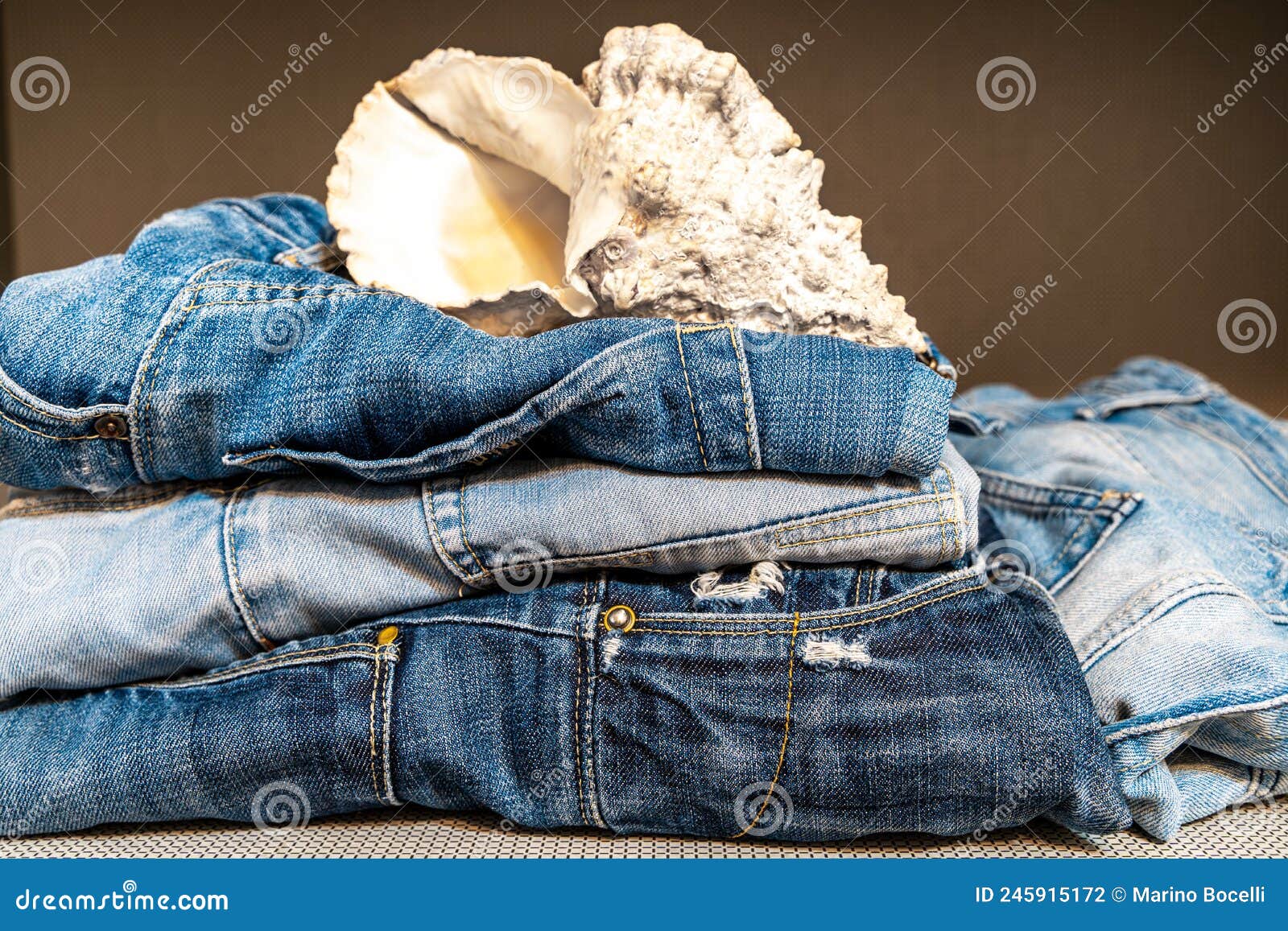 Stack of Jeans of Various Types and Shades of Blue with a Shell on Top ...