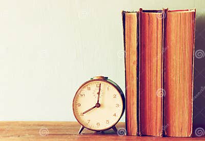 Stack of Old Books and Old Clock Over Wooden Table . Filtered Image ...