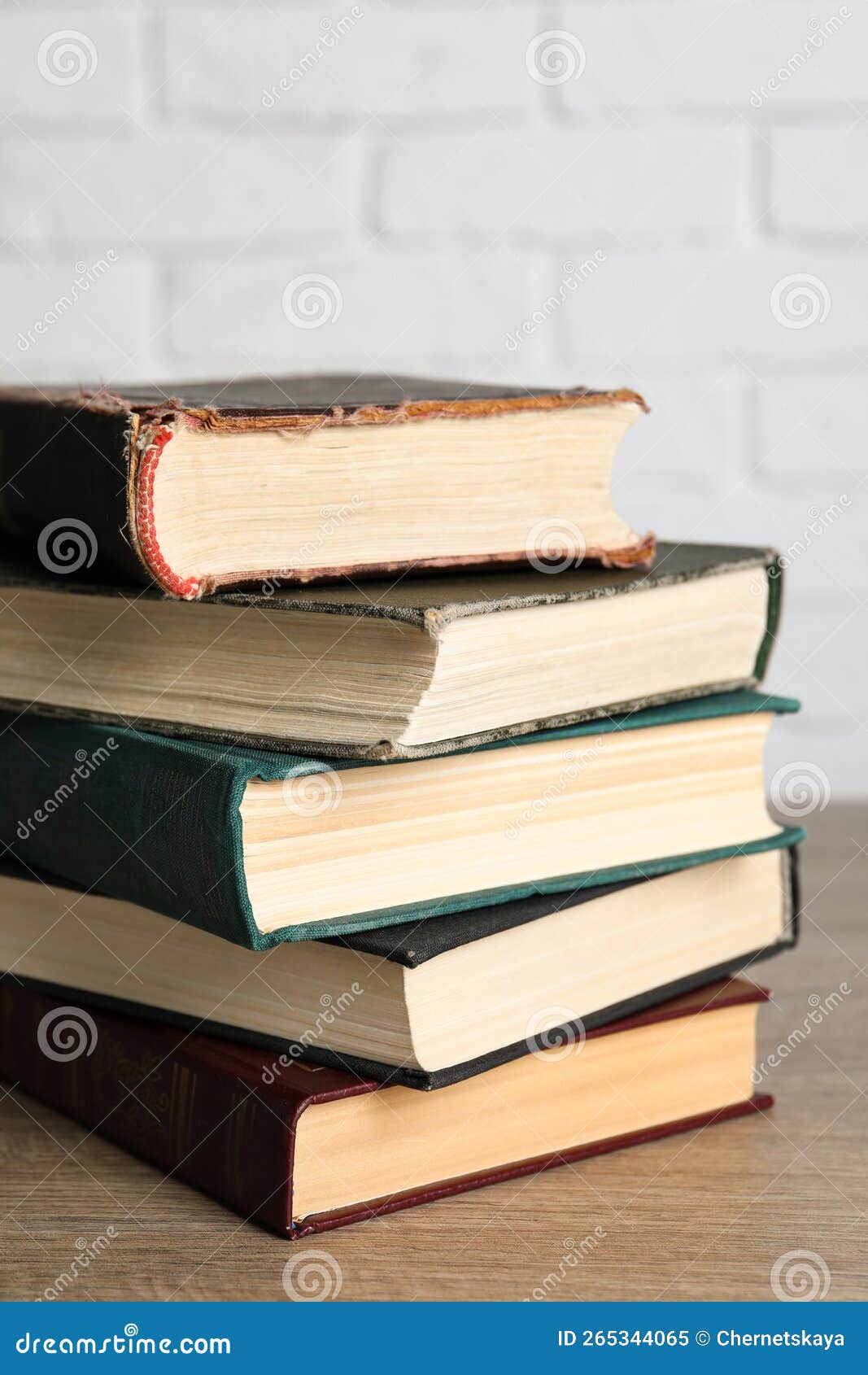 Stack of Old Hardcover Books on Wooden Table Near White Brick Wall ...