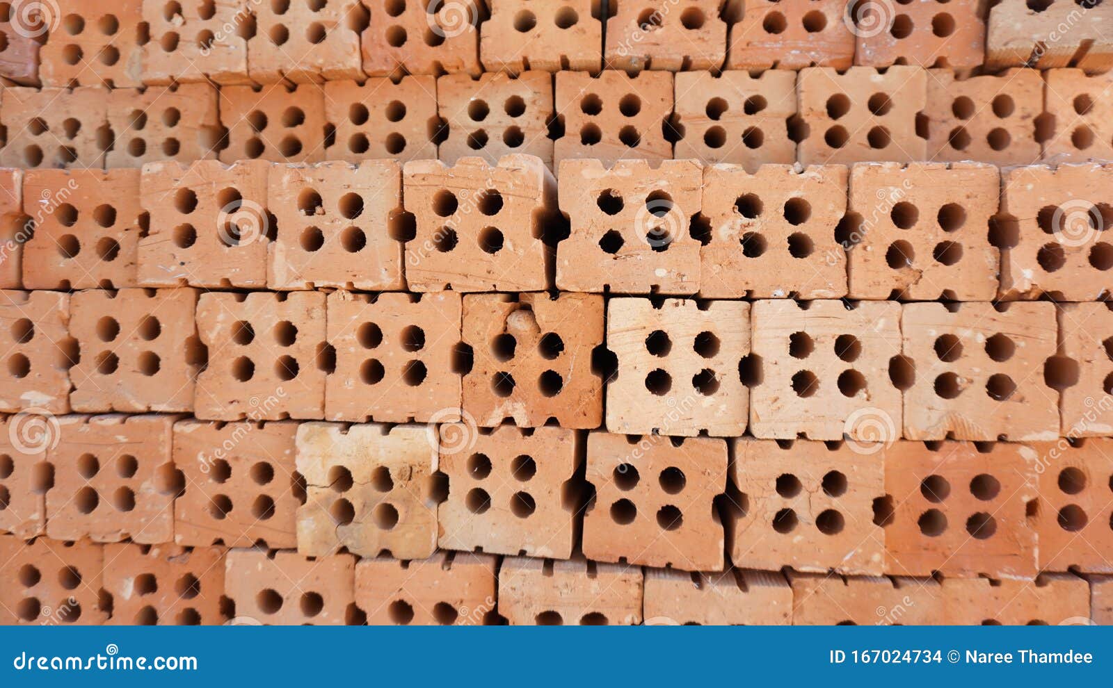A Stack of Orange 4 Hole Bricks in Construction Site with Brick Wallthe ...