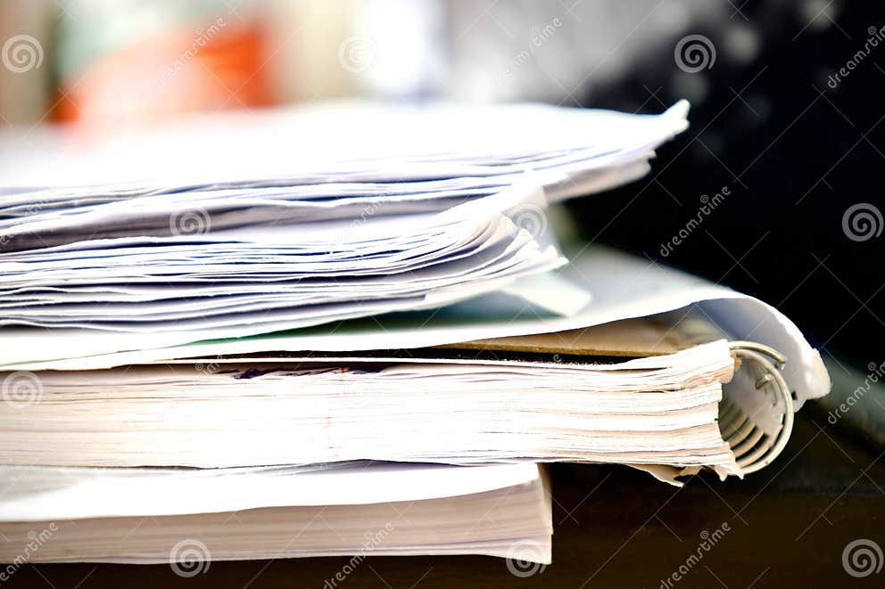 A Stack of Papers and a Spiral Notebook on a Table Stock Image - Image ...
