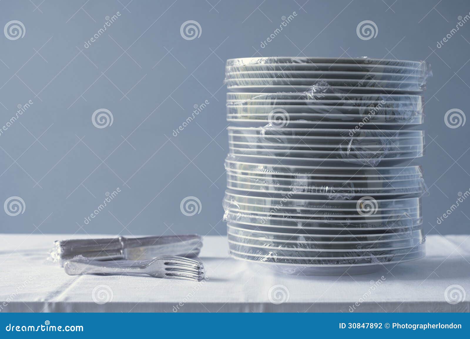Stack of Plates and Cutlery Wrapped in Plastic on Table Stock Photo ...