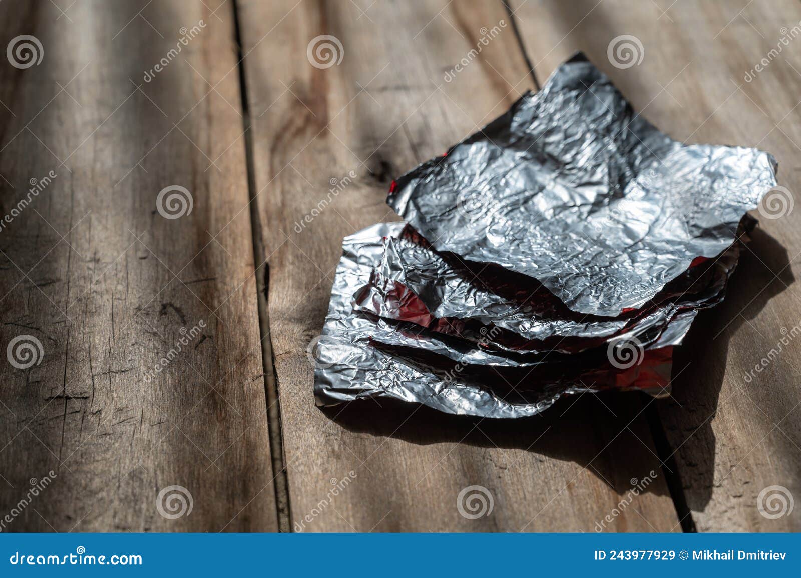 A Stack of Rectangular Aluminum Candy Wrappers Against a Wooden ...