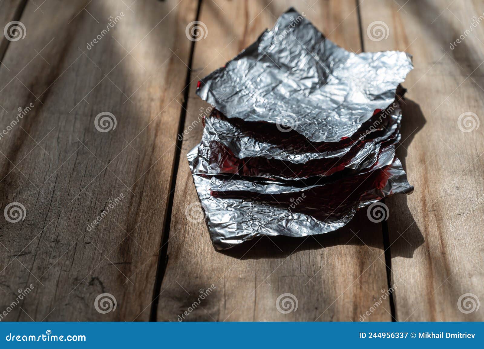 A Stack of Rectangular Aluminum Candy Wrappers Against a Wooden ...