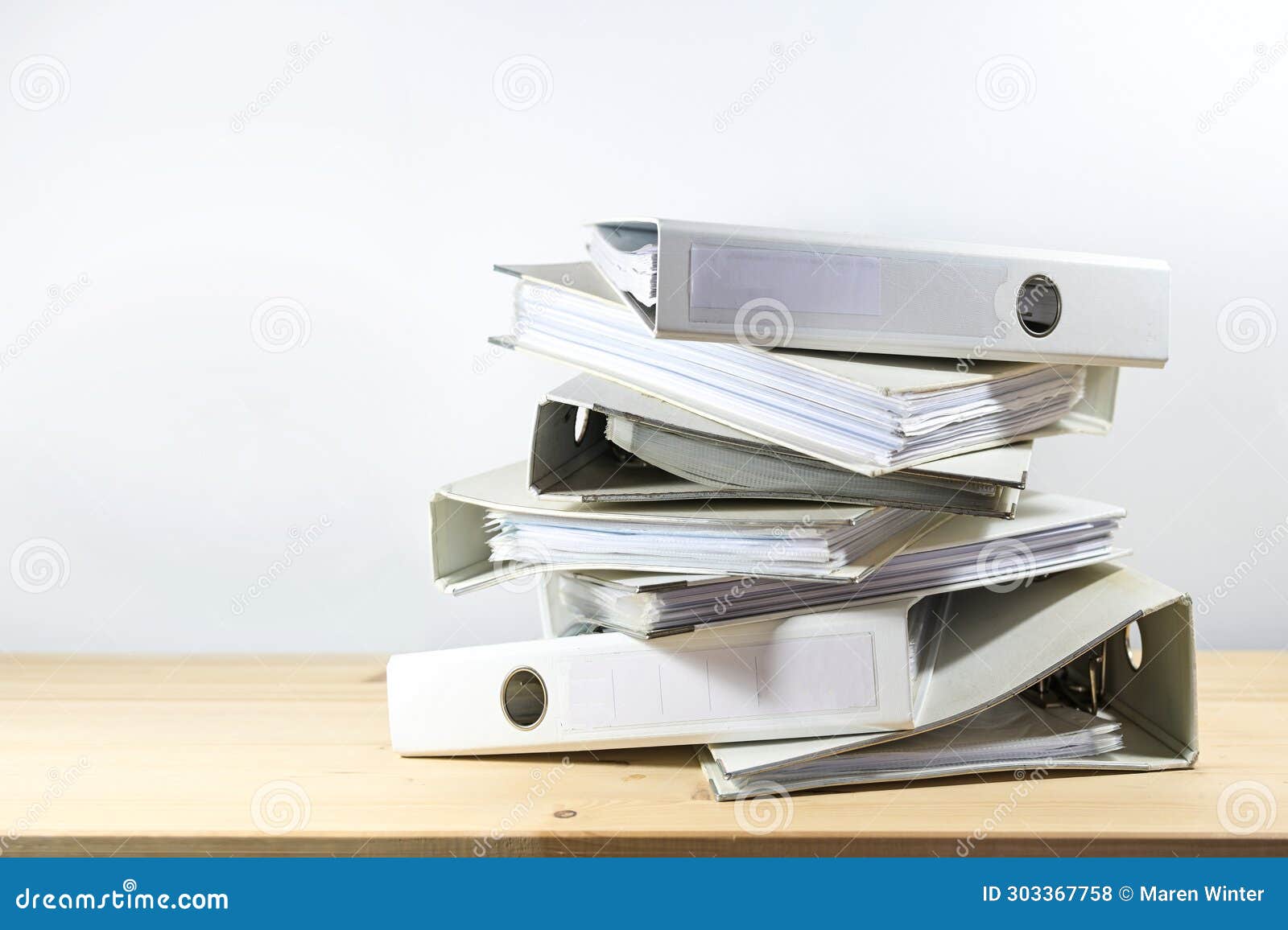 Stack of Ring Binders on a Wooden Office Desk Against a Light Gray Wall ...