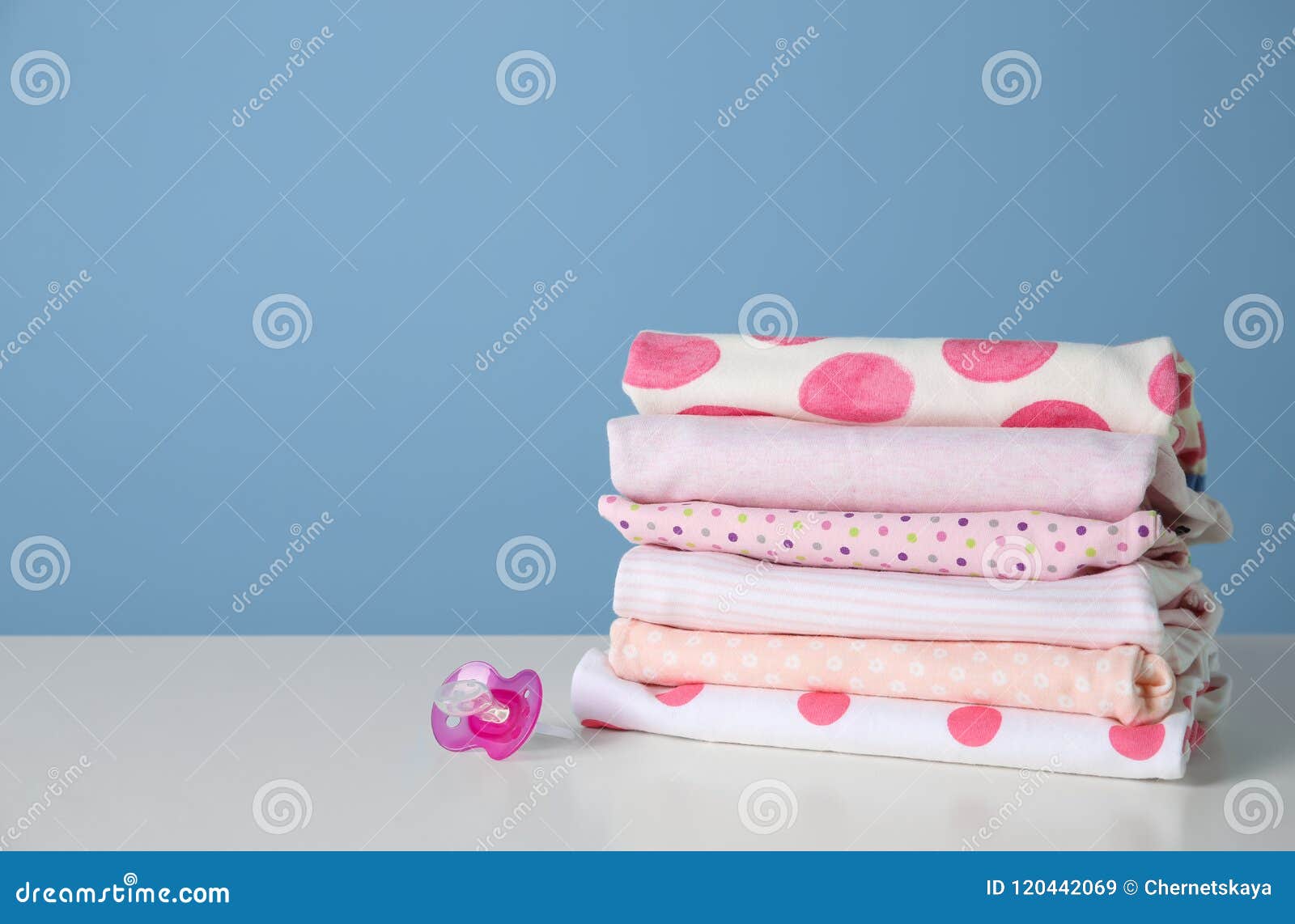 Stack of Stylish Child Clothes and Pacifier on Table Stock Image ...