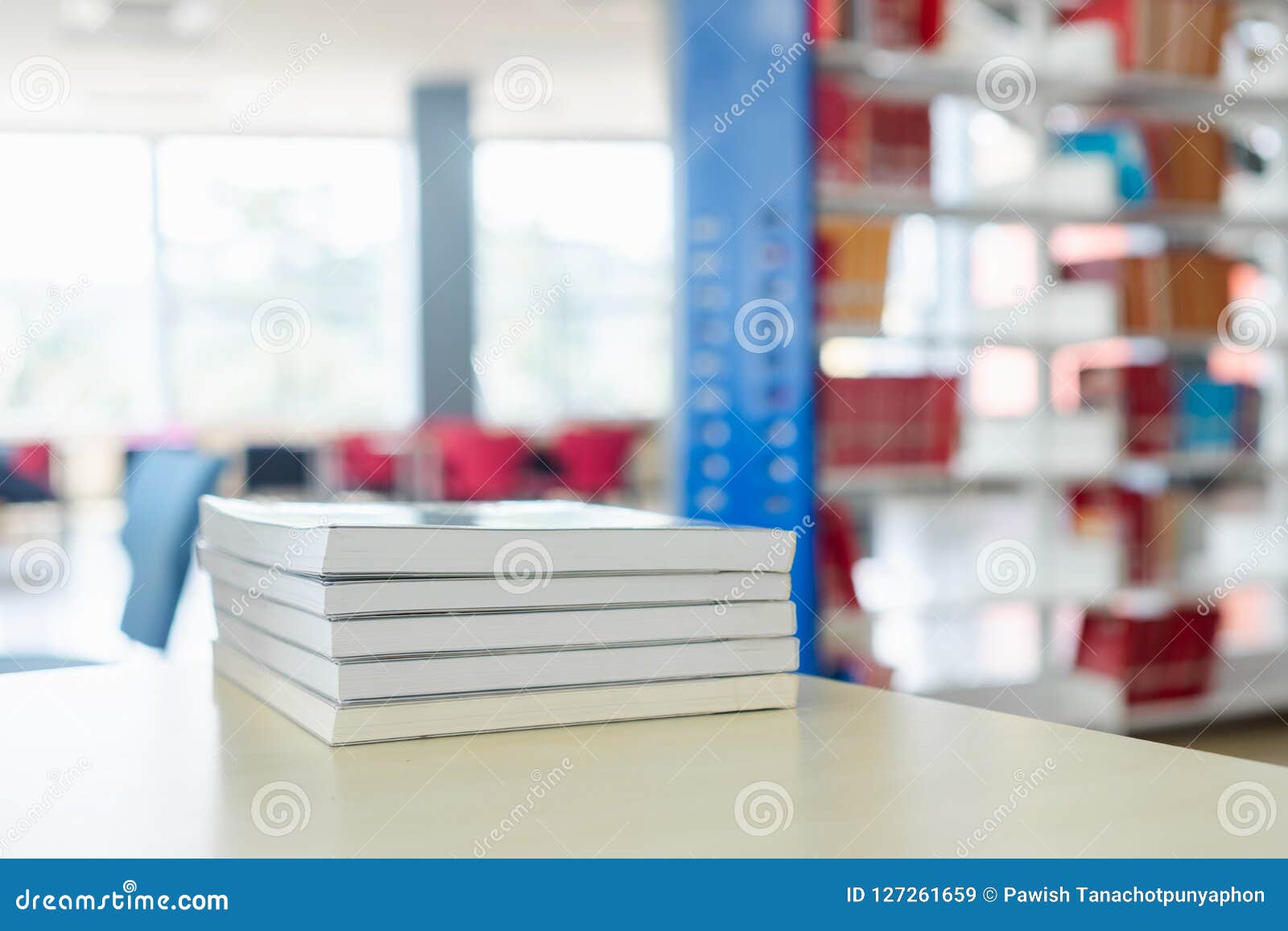 Stack of Textbooks on Wooden Table with Blurred Bookshelf in Lib Stock ...