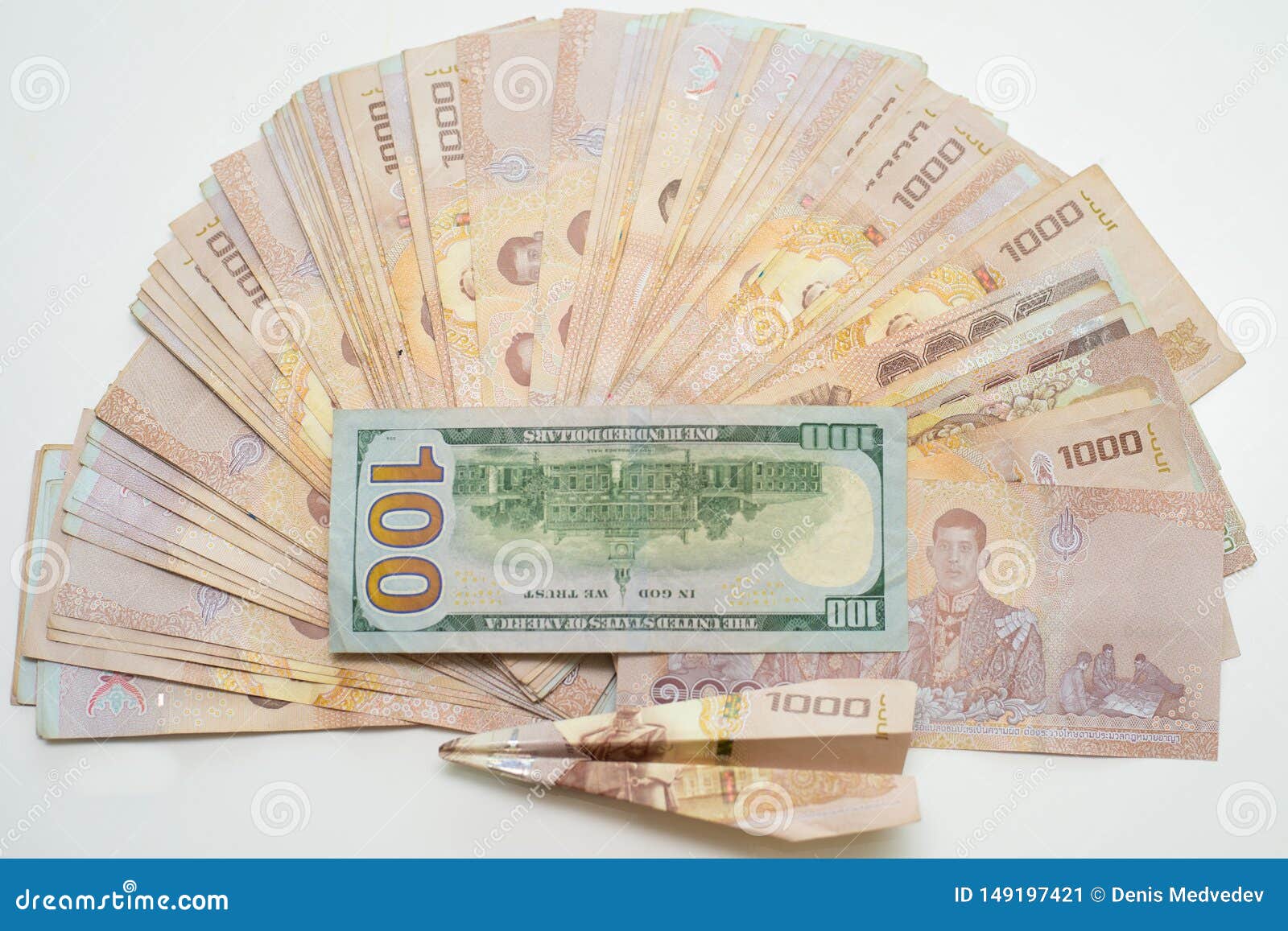 A Stack of Thai Baht and a Hundred Dollar on a White Table with a Plane ...