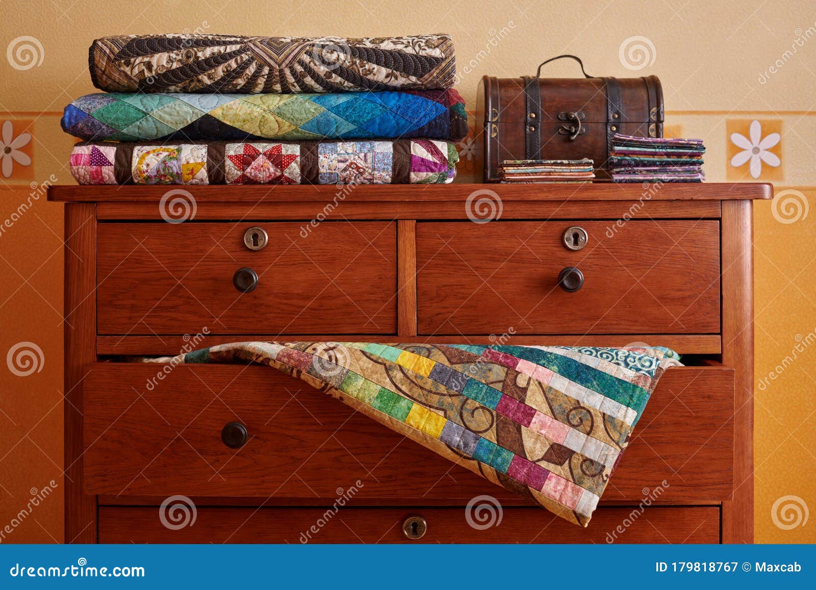 Stack of Traditional Quilts and Wooden Chest on Chest of Drawers Stock ...