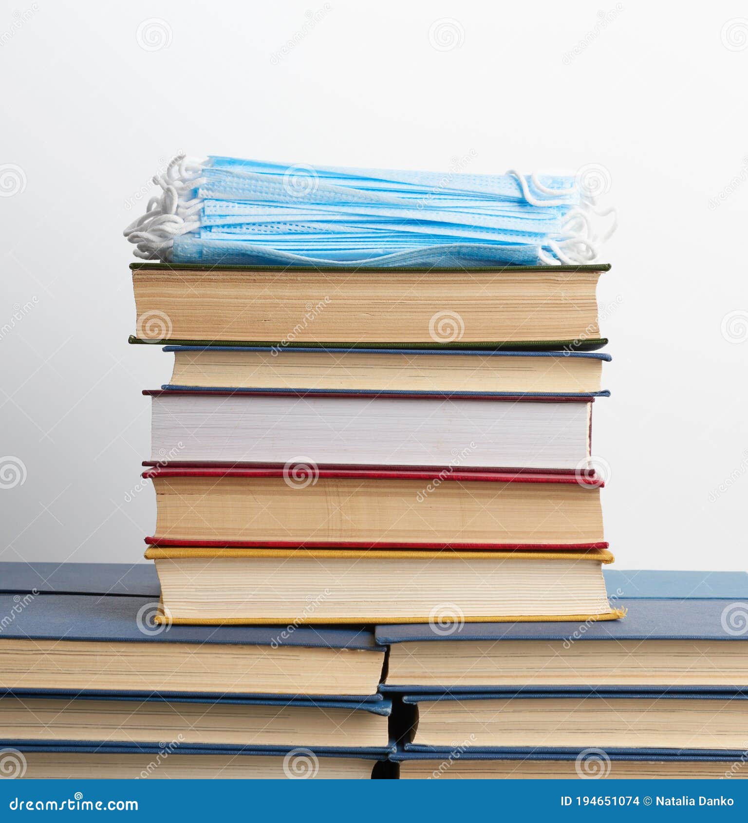 Stack of Various Books and Disposable Medical Masks on a White ...