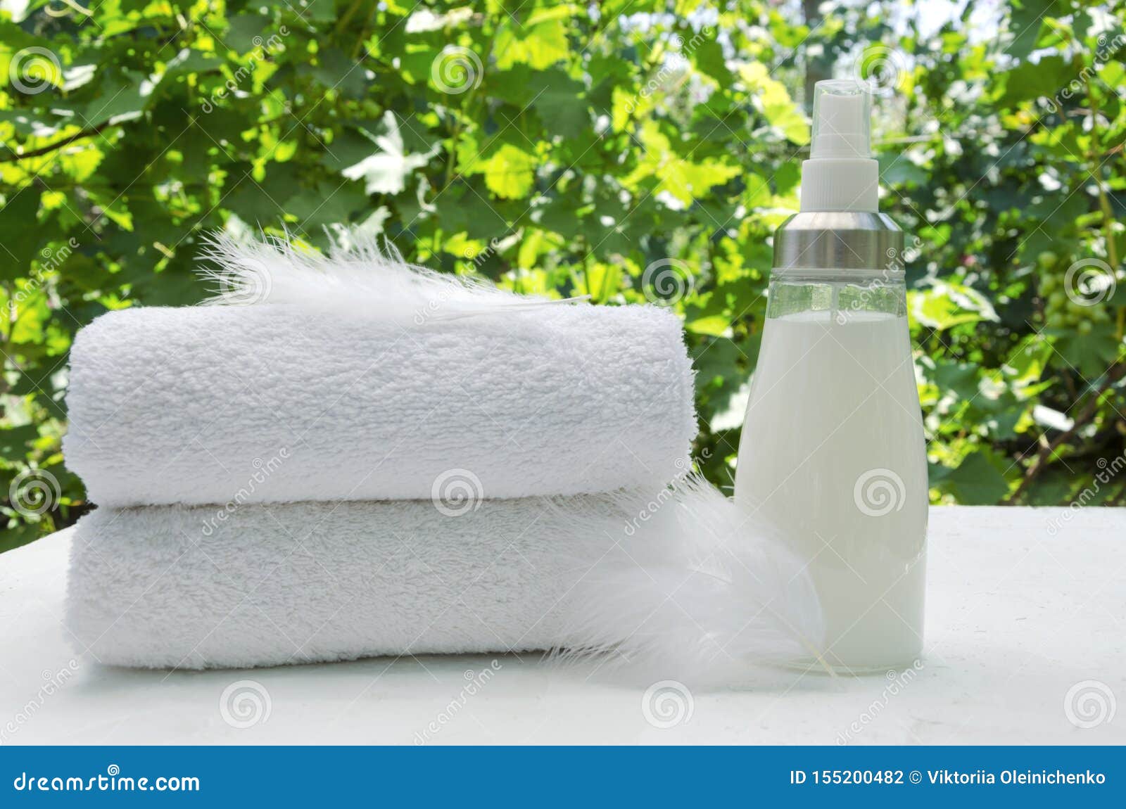 Stack of White Towels, Glass Bottle of Softener and Feathers As a ...