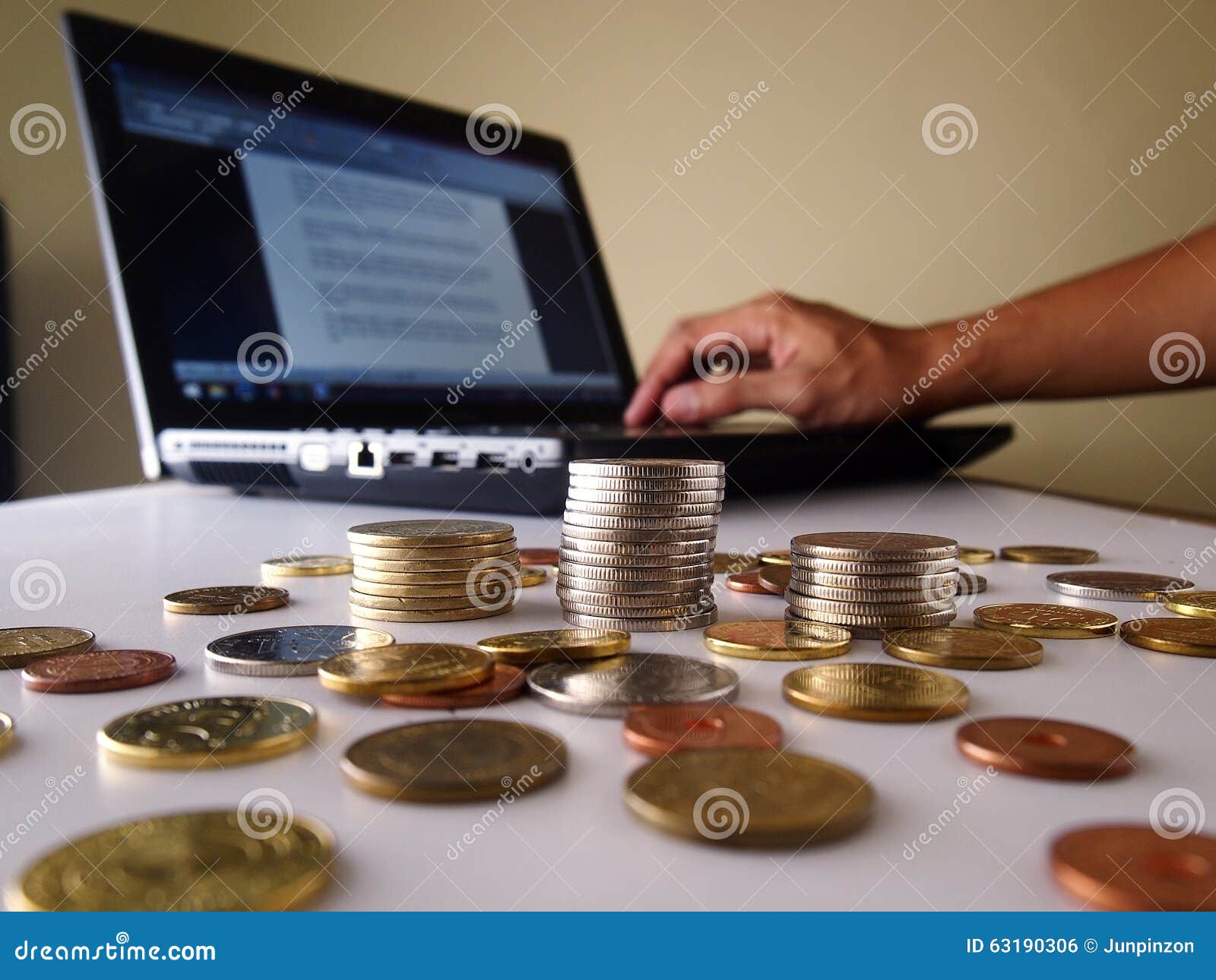 Stacks of Coins and a Hand Working on a Laptop Computer Stock Photo ...