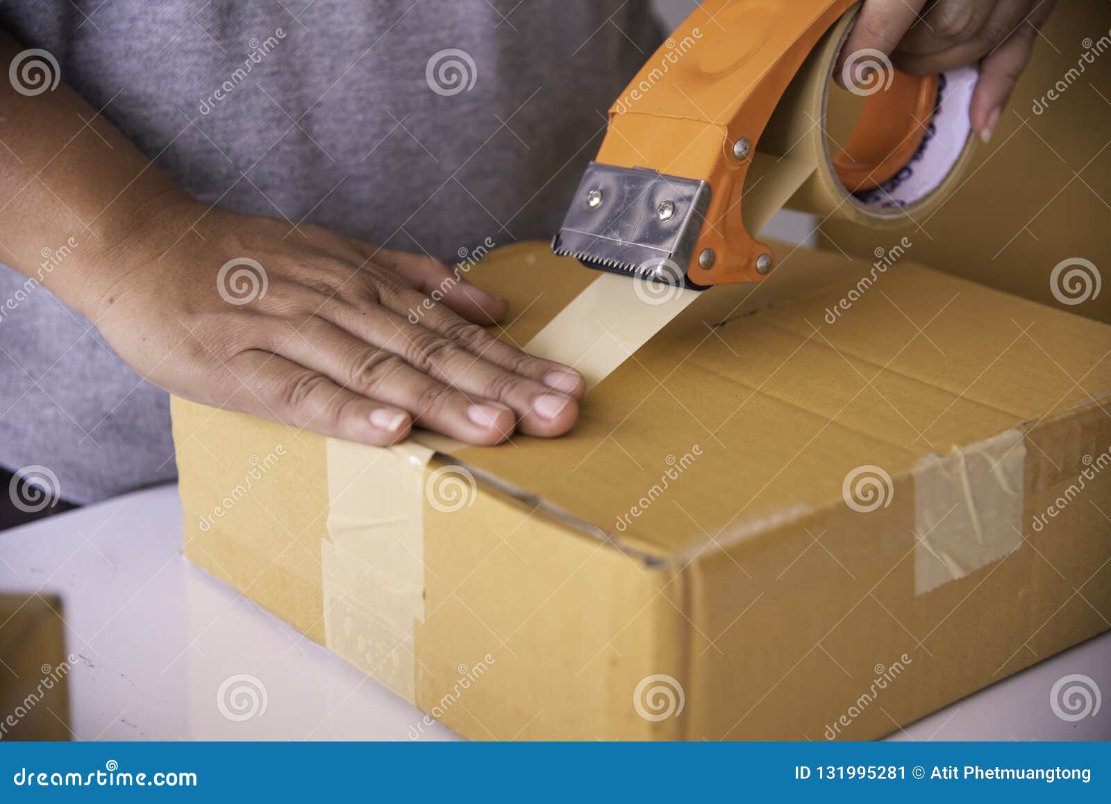 The Staff is Using the Tape To Pack the Package Goods To the Customer ...