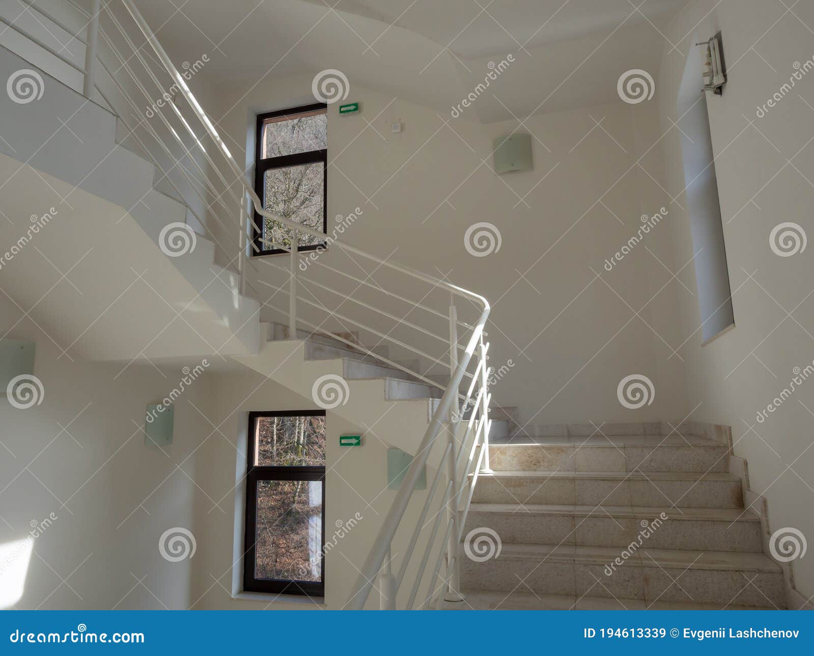 A Stairwell with Light Steps with White Railings and White Walls and ...