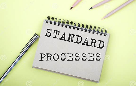 STANDARD PROCESSES Text on the Notebook with Pen on Yellow Background ...
