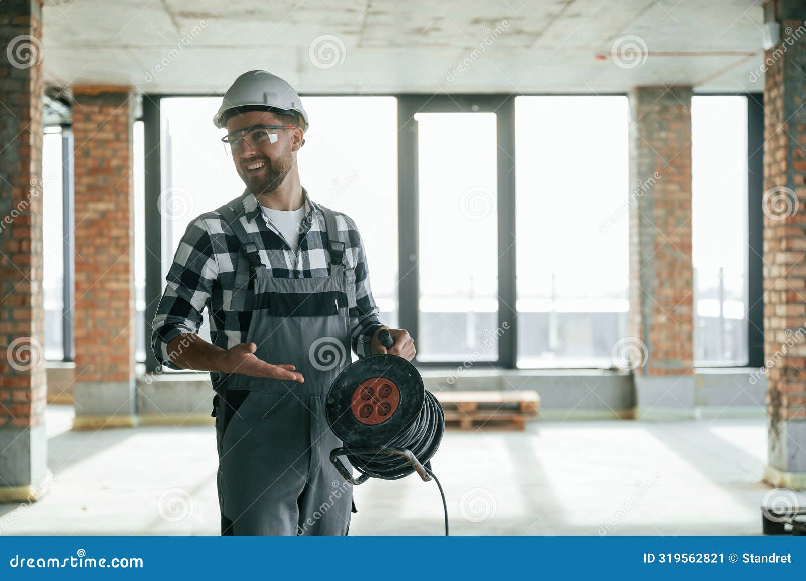 Standing and Holding Wires in Hands. Construction Worker in Uniform in ...