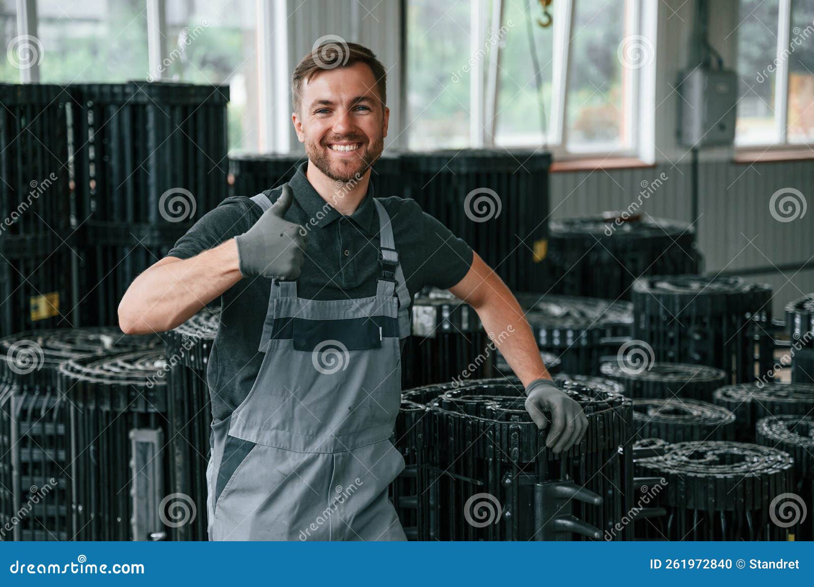 Standing and Smiling. Man in Uniform is in Workstation Developing ...