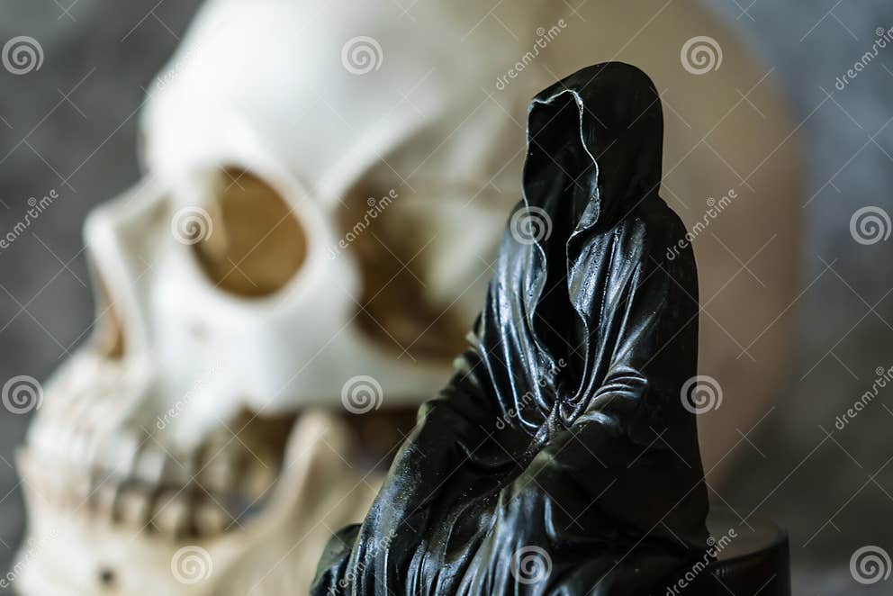 A Statue of a Grim Reaper Sitting and Skull Background Stock Photo ...
