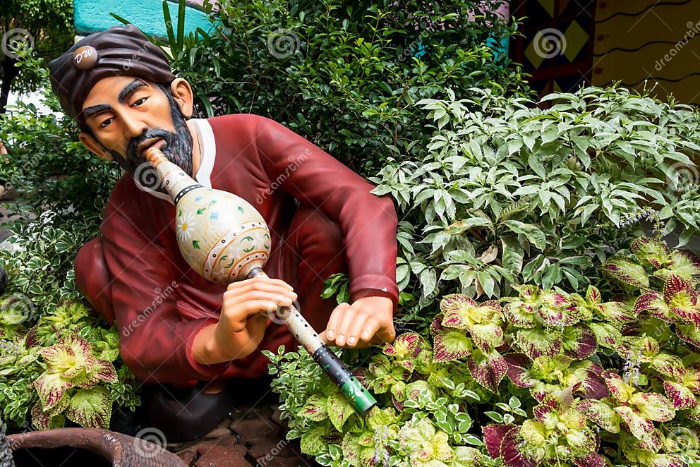 A Statue of a Man Blowing a Pipe in a Park. Stock Photo - Image of ...