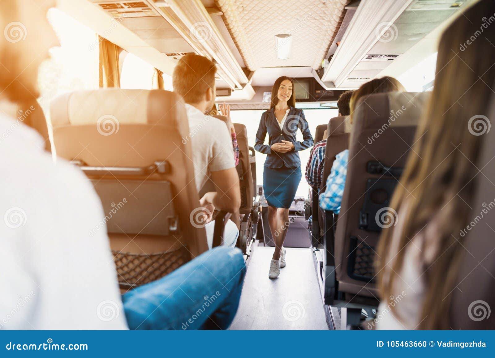 A Stewardess is Posing on the Bus. it Stands between the Rows of Seats ...