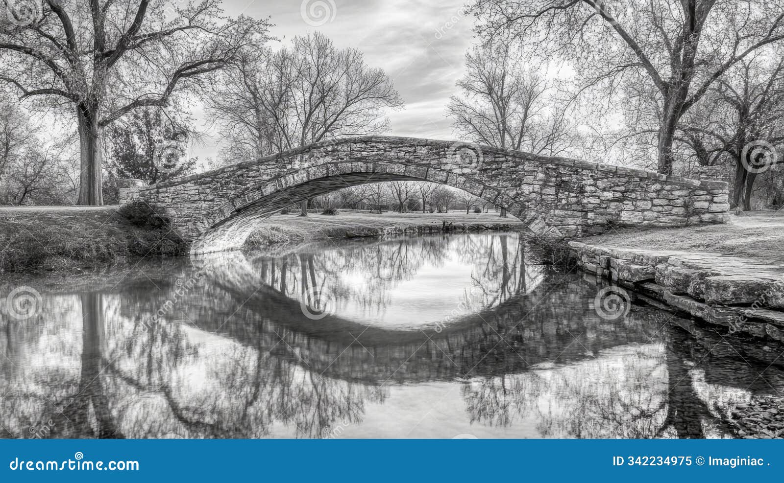 Stone Arch Bridge Over a Stream with Bare Trees Reflecting in the Water ...