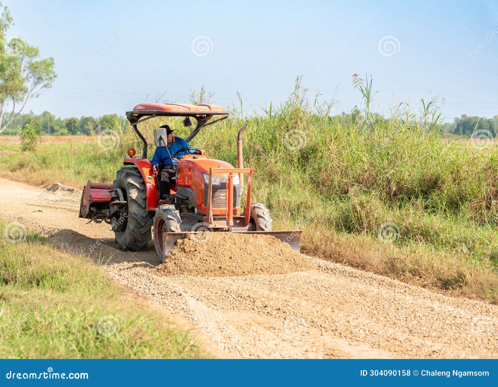 A Stone-plowing Tractor is Leveling the Road Surface Stock Photo ...