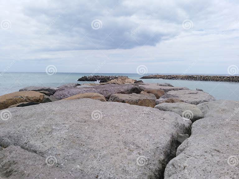 A Stone Wave Breaker Facing the Ocean Under the Cloudy Sky. Stock Image ...