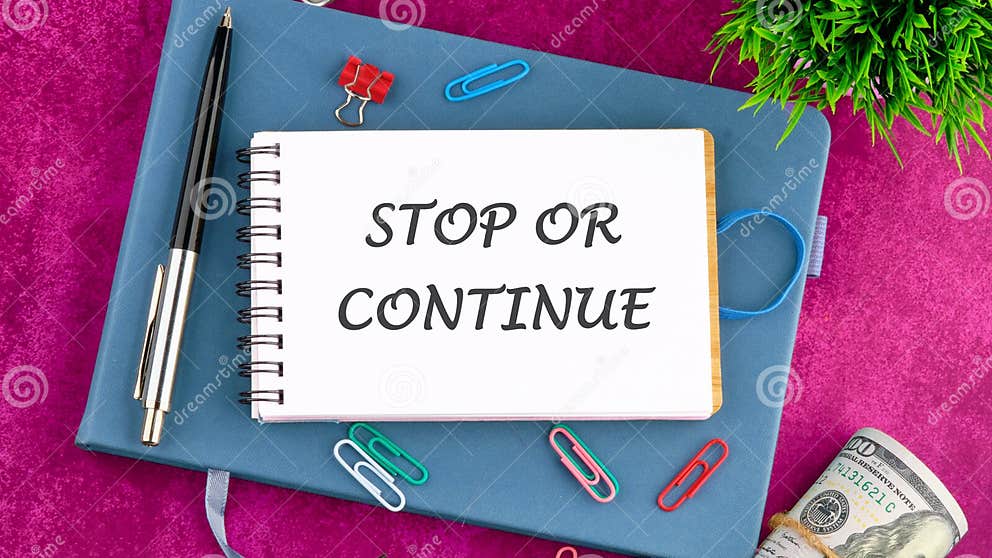 STOP or CONTINUE Written in a Notebook in Front of an Abstract ...