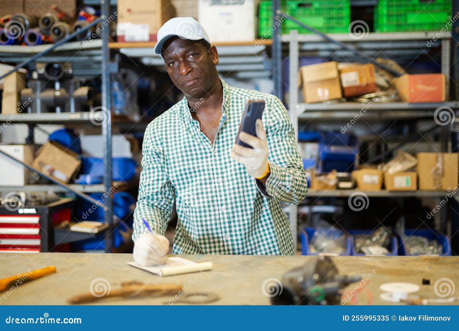 Storehouse Worker Standing at Workbench and Making Notes, Using ...