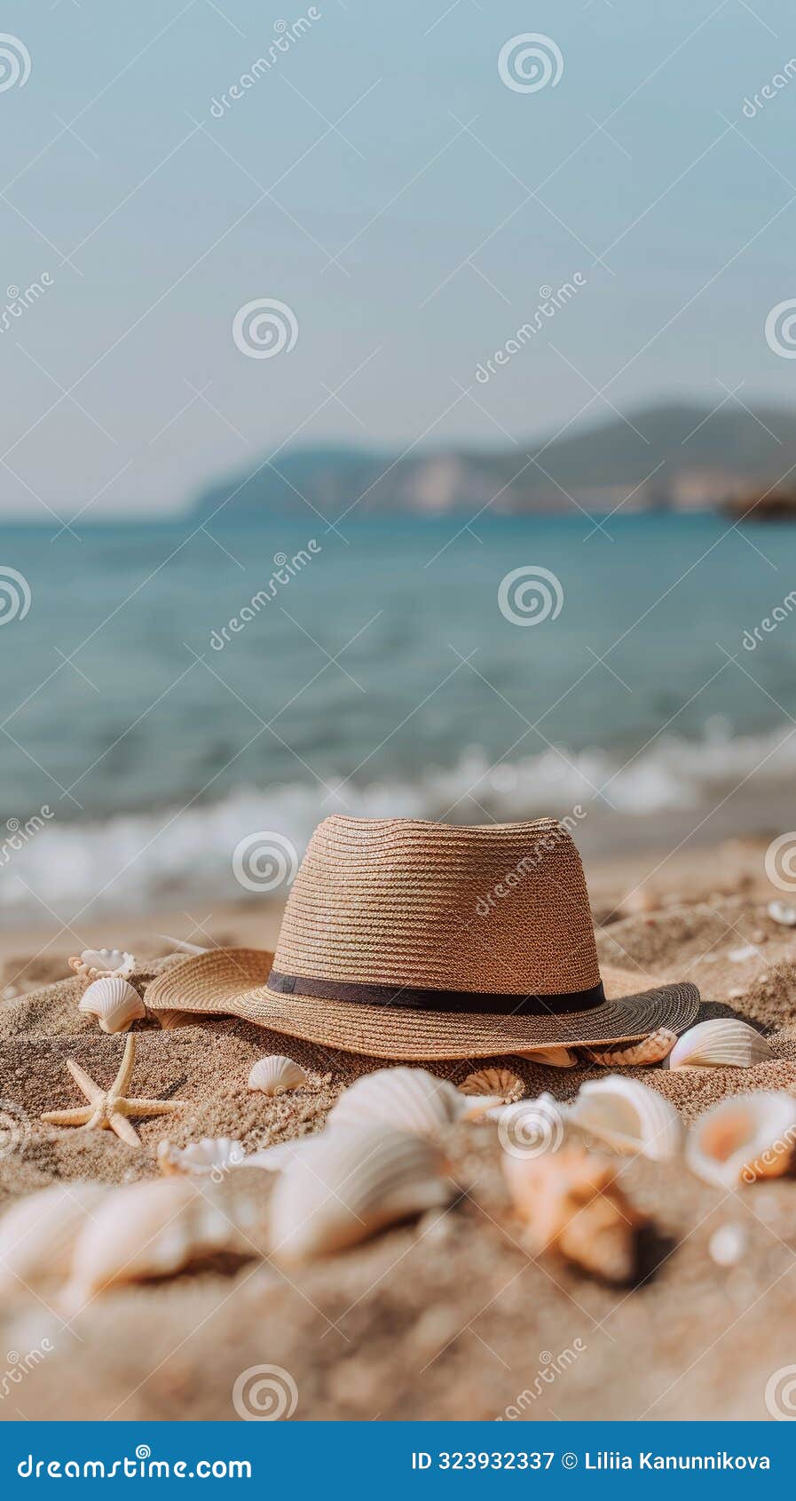 A Straw Hat and Seashells Lie on the Sandy Beach, with the Ocean Waves ...