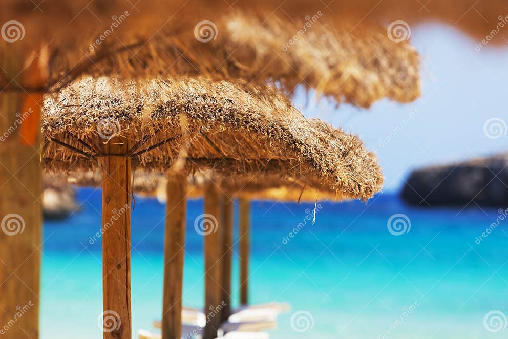 Straw Parasols and Beds on the Sandy Beach. Stock Photo - Image of ...