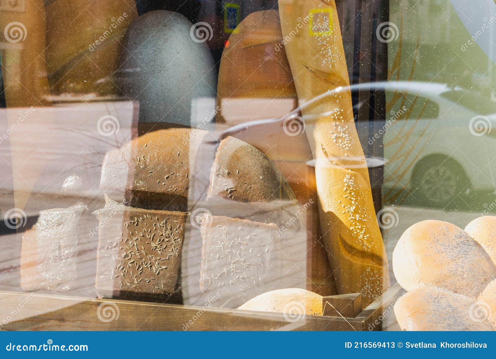 A Street and a Car are Reflected in the Window of a Bakery with Rolls ...