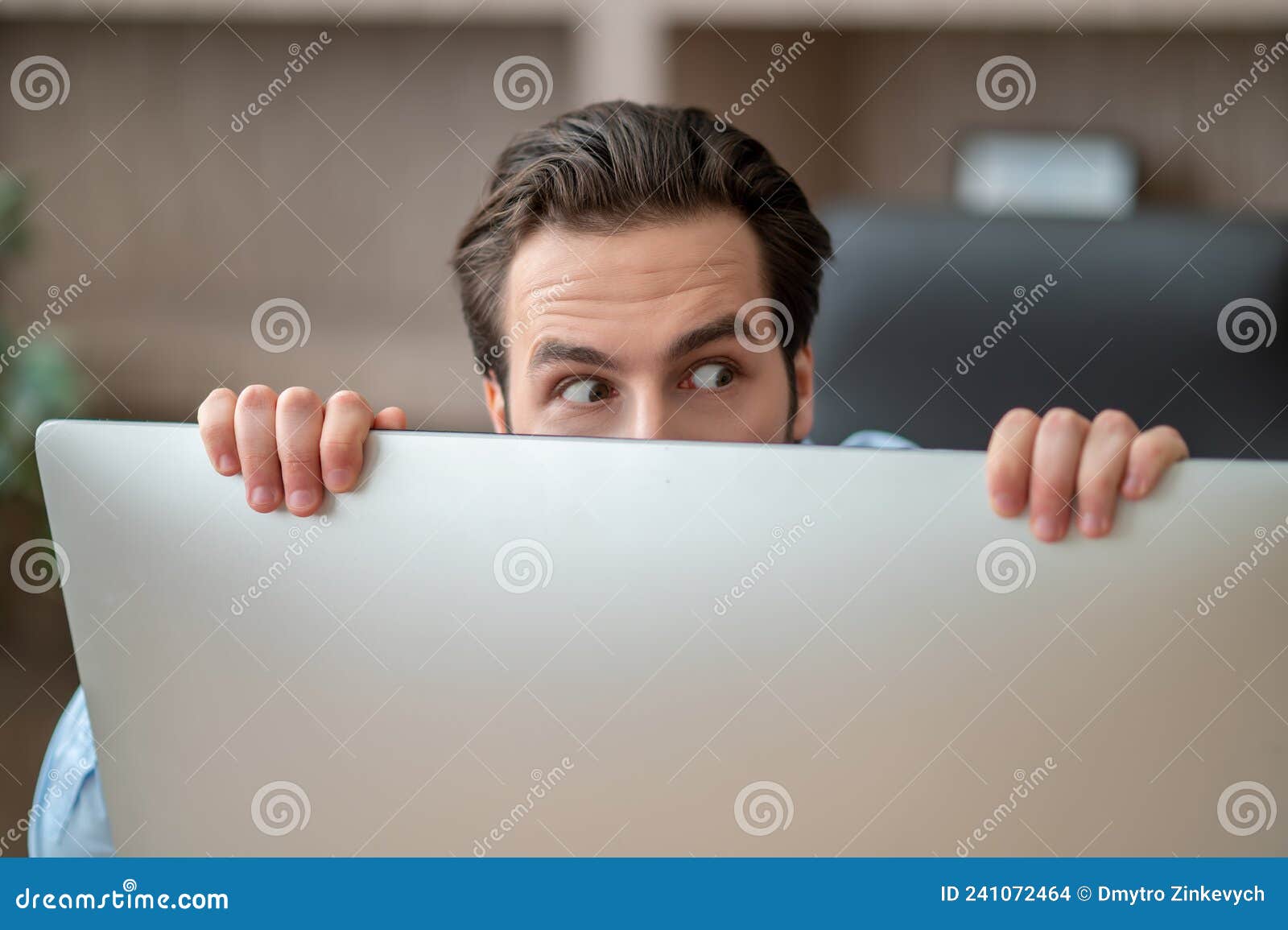 A Dark-haired Man Hiding Behind the Computer and Looking Stressed Stock ...
