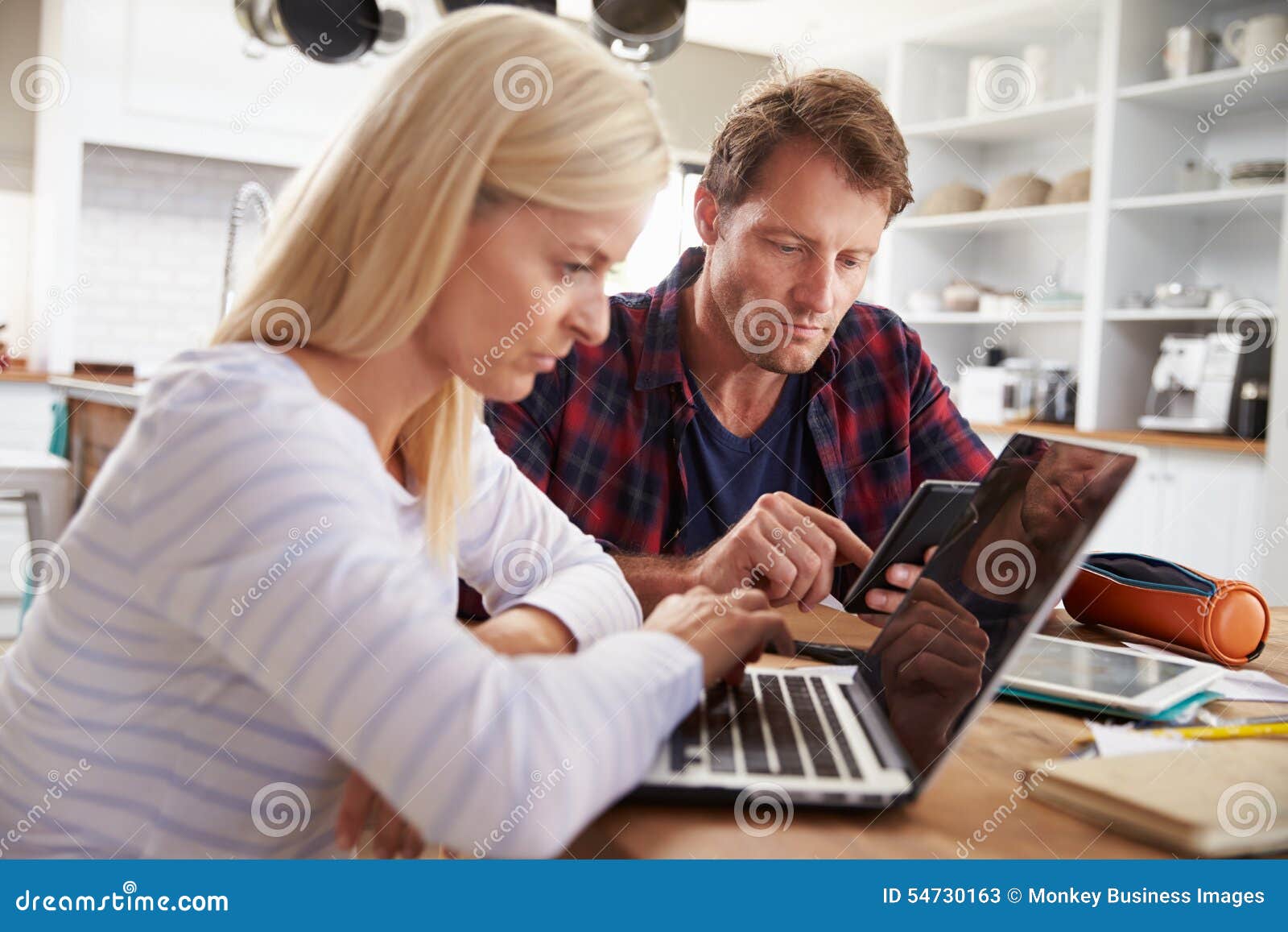 Stressed Couple Sitting in Their Kitchen Using Computers Stock Image ...