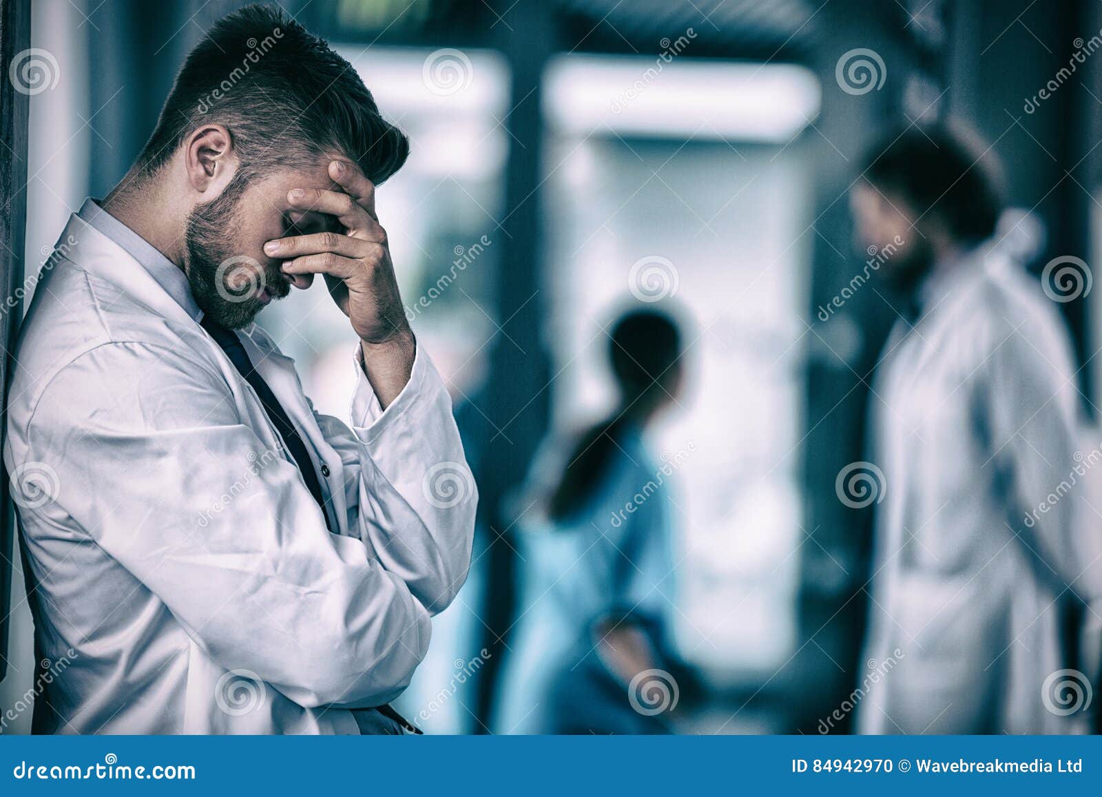 Stressed Doctor Standing Against Wall in Hospital Stock Photo - Image ...