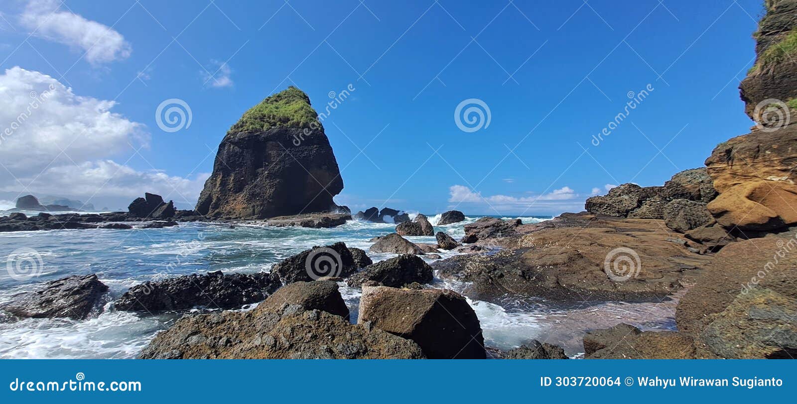 A Stretch of Black Rocks on the Beach with a Blue Sky and White Clouds ...