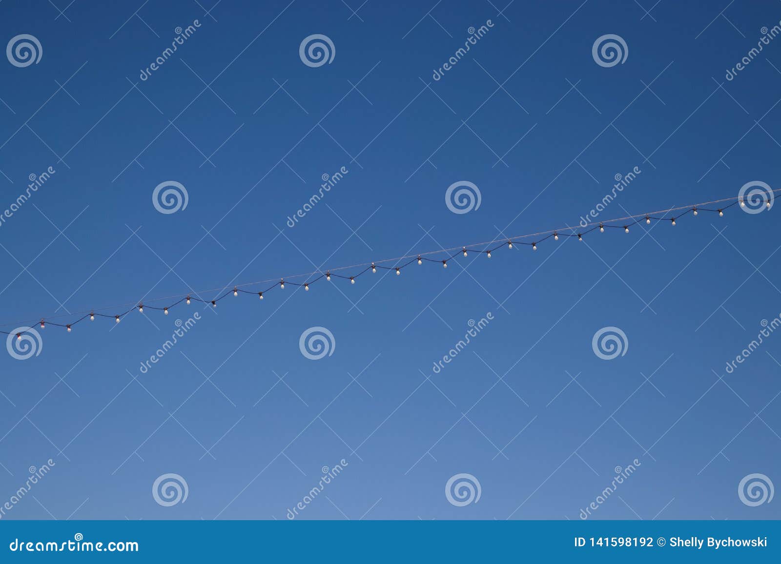 String of Light Bulbs Hanging in a Line Against a Clear Blue Sky Stock ...