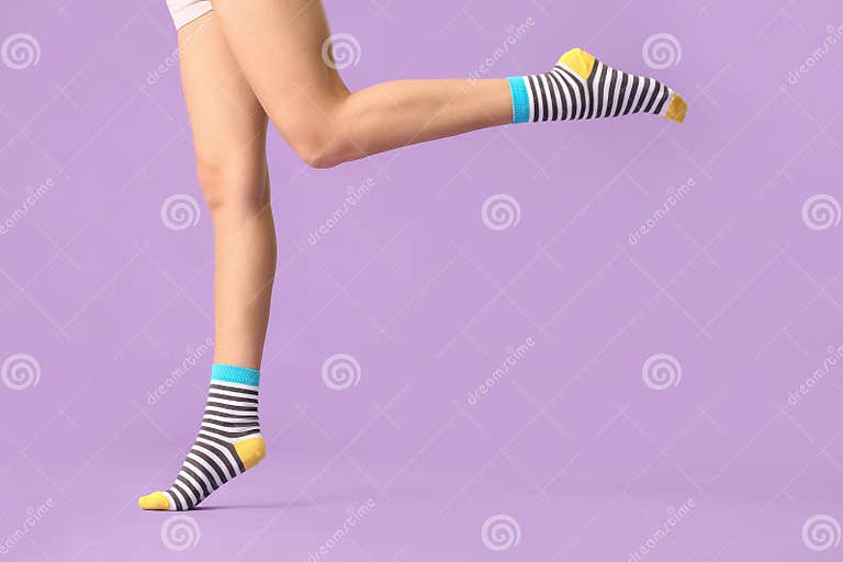 Legs Of Young Woman In Striped Socks On Color Background Stock Image