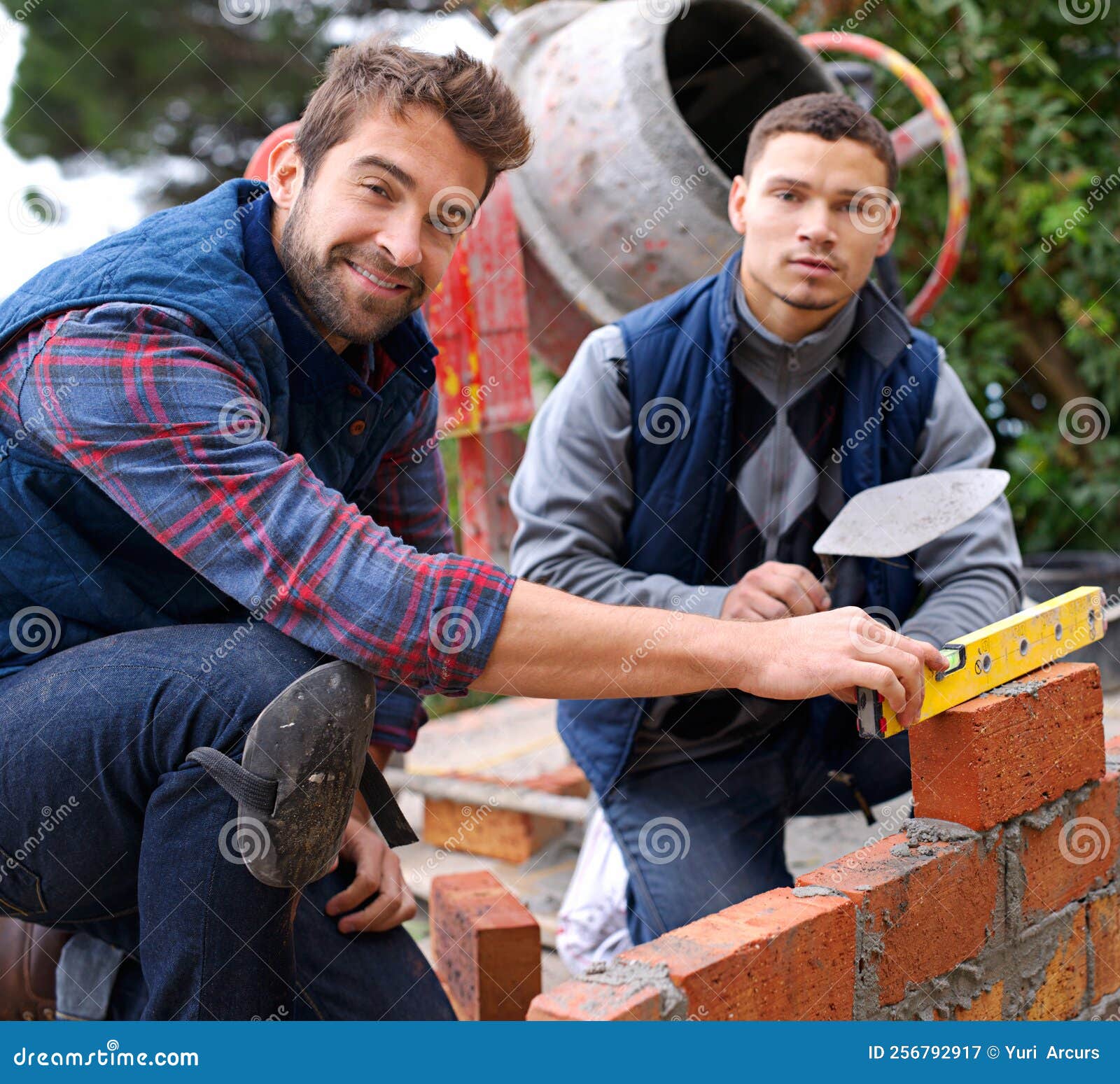 Strong Walls and Bonds. Portrait of a Bricklayer and His Apprentice at ...