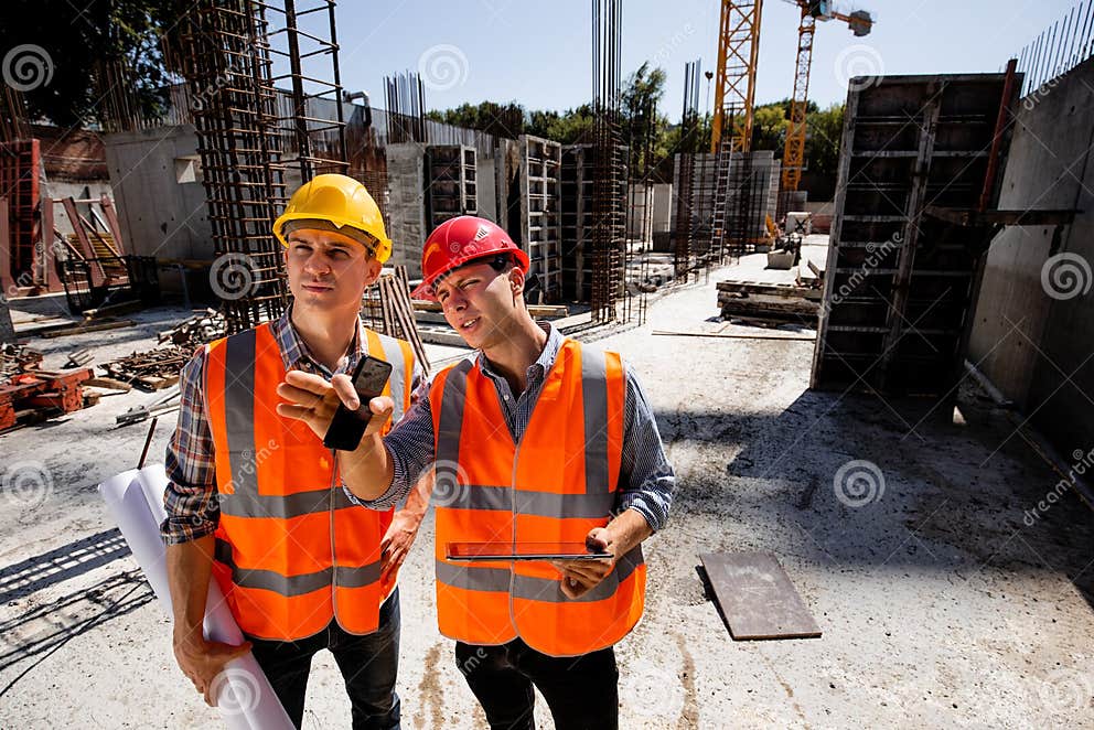 Structural Engineer and Architect Dressed in Orange Work Vests and Hard ...
