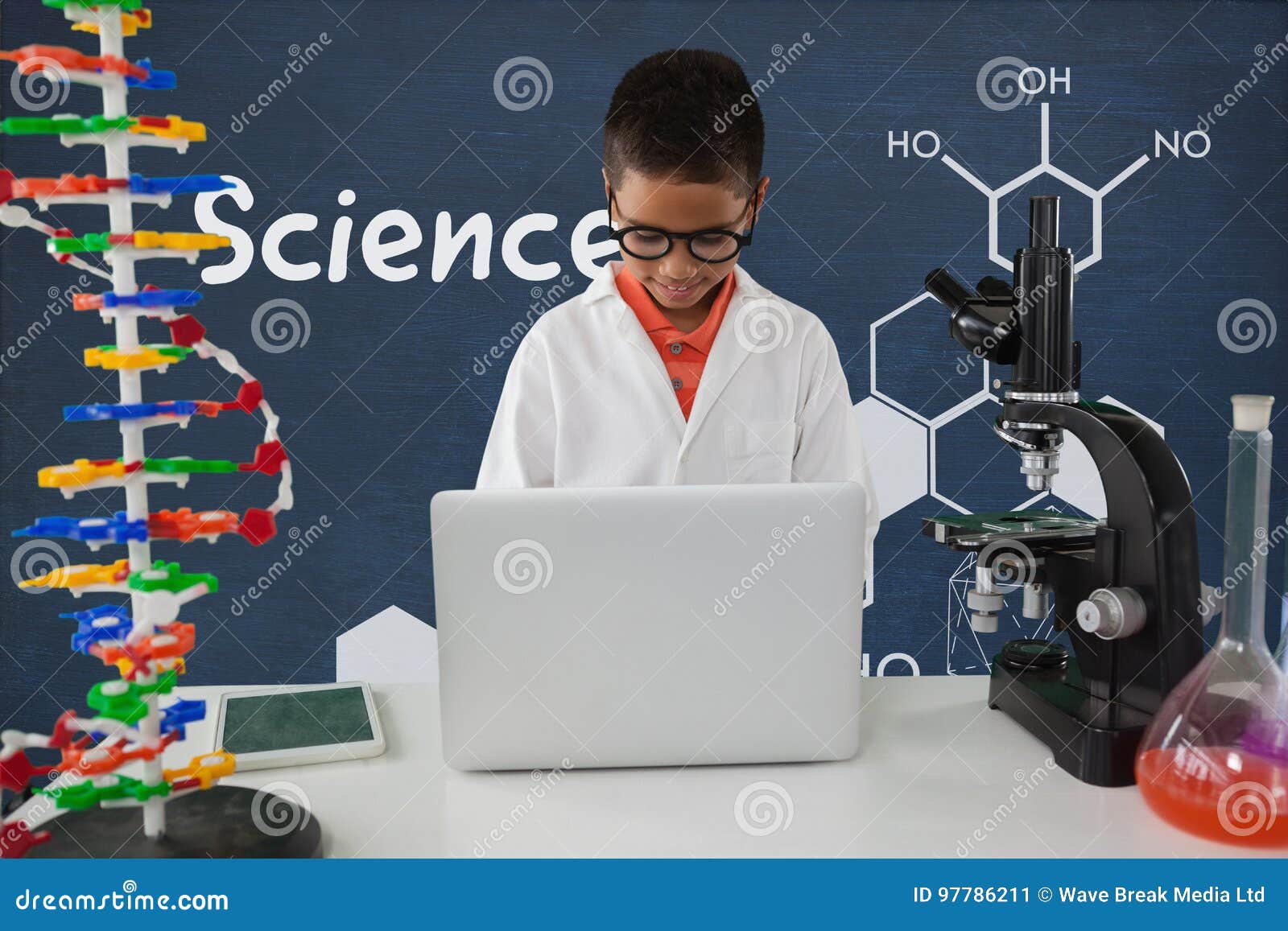 Student Boy at Table Using a Computer Against Blue Blackboard with ...