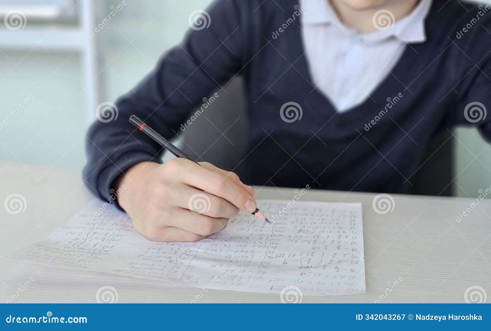Student Focused on Writing Notes while Seated at a Table with a Pen in ...